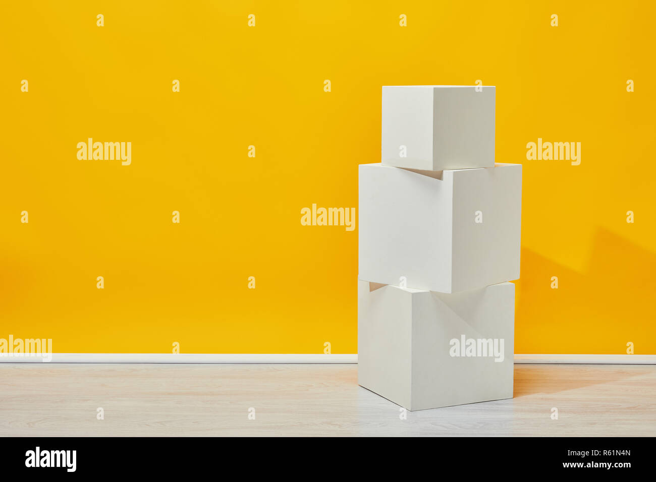 simple white plaster cubes arranged vertically near yellow wall Stock ...