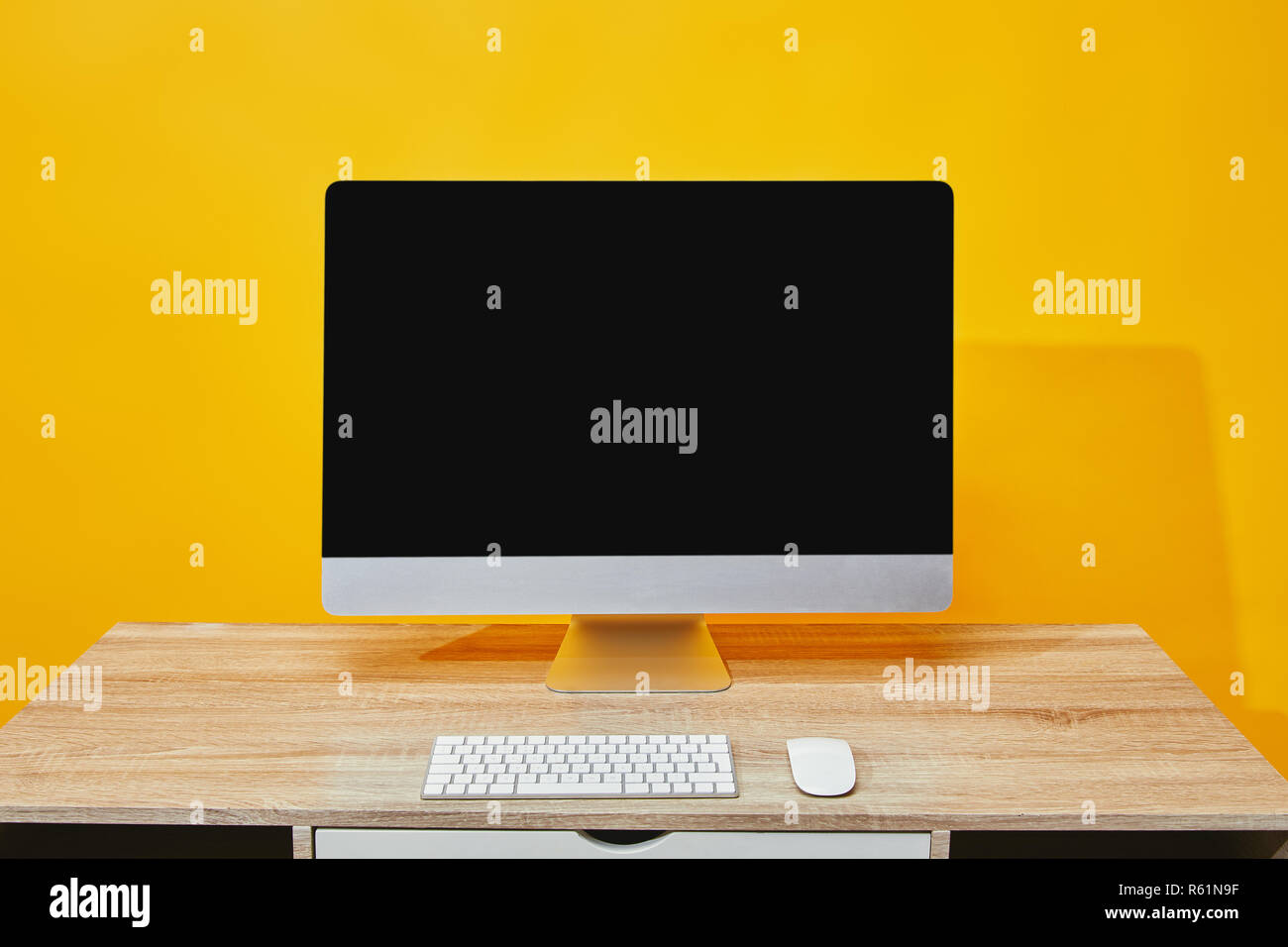 Workspace with computer,keyboard and mouse at wooden table on yellow ...