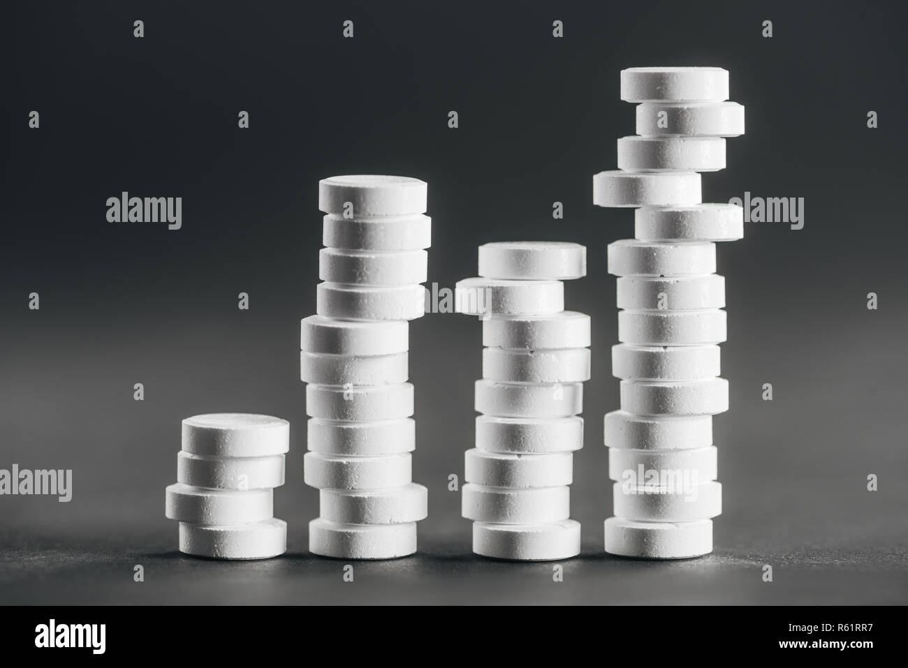 close up view of stacks of white pills placed in rows on grey Stock ...