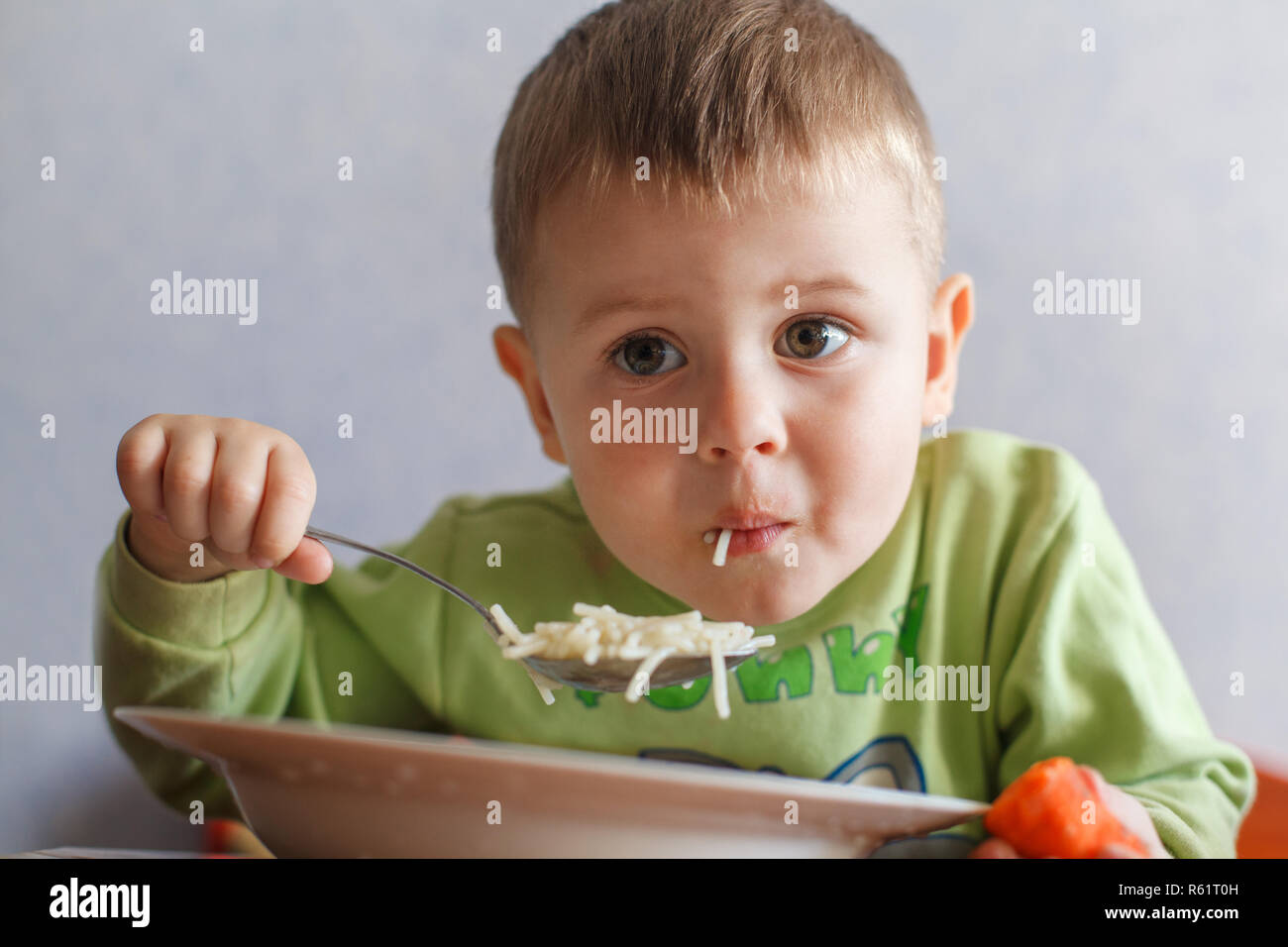 Hungry child eats lunch with big appetite. Cute boy eats pasta. Food ...