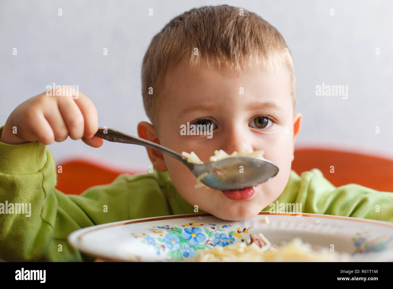 Hungry child eats lunch with big appetite. Cute boy eats pasta. Food ...