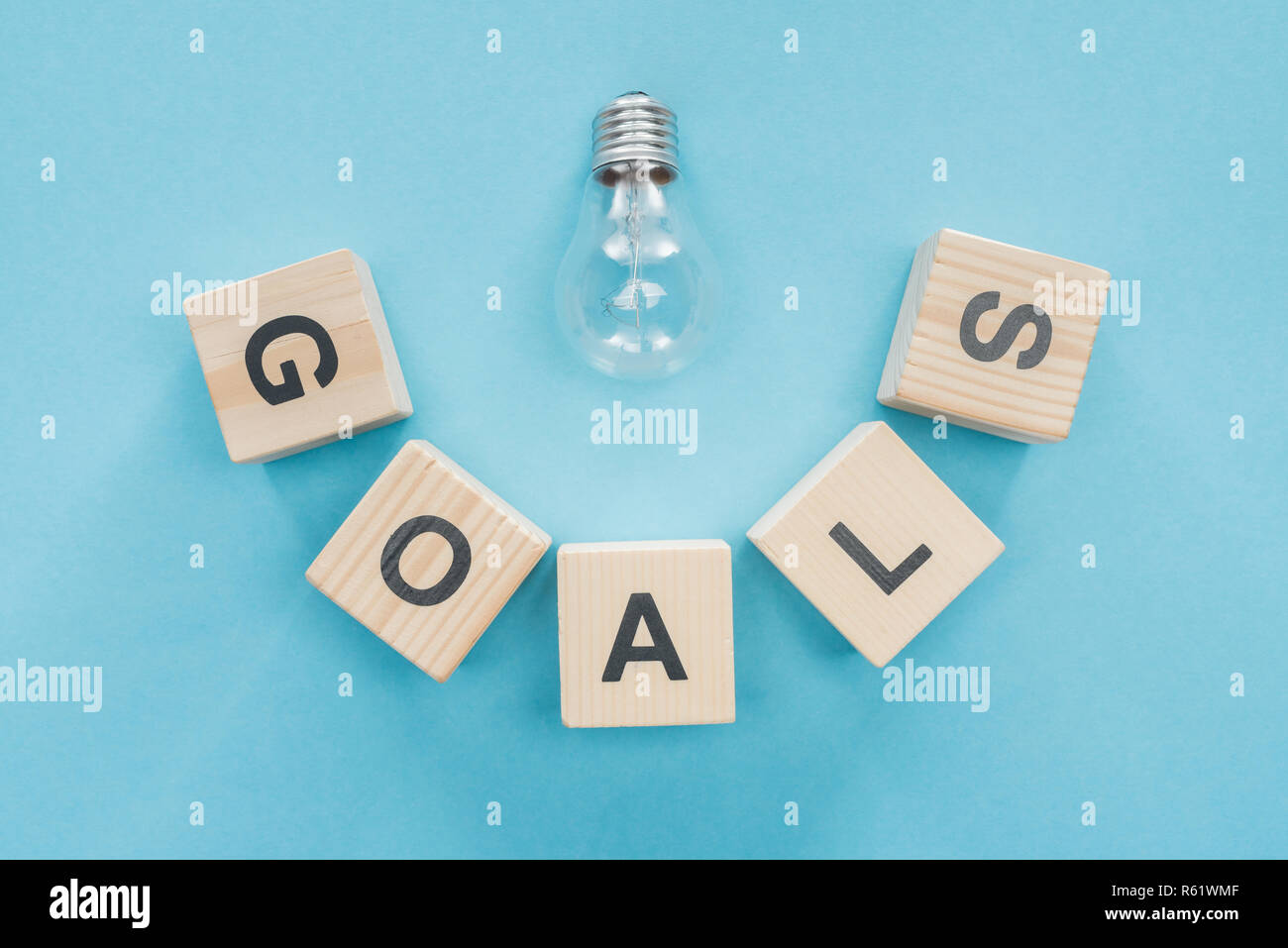 top view of light bulb over 'goals' word made of wooden blocks on blue ...