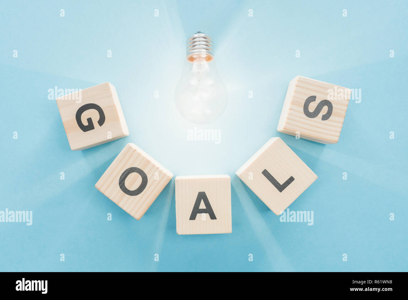 top view of glowing light bulb over 'goals' word made of wooden blocks ...