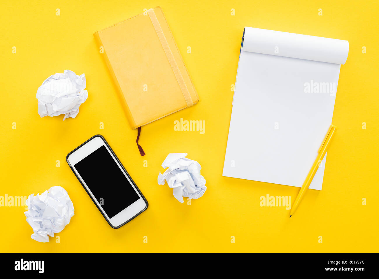 blank notebook, crumbled paper balls and smartphone with blank screen ...