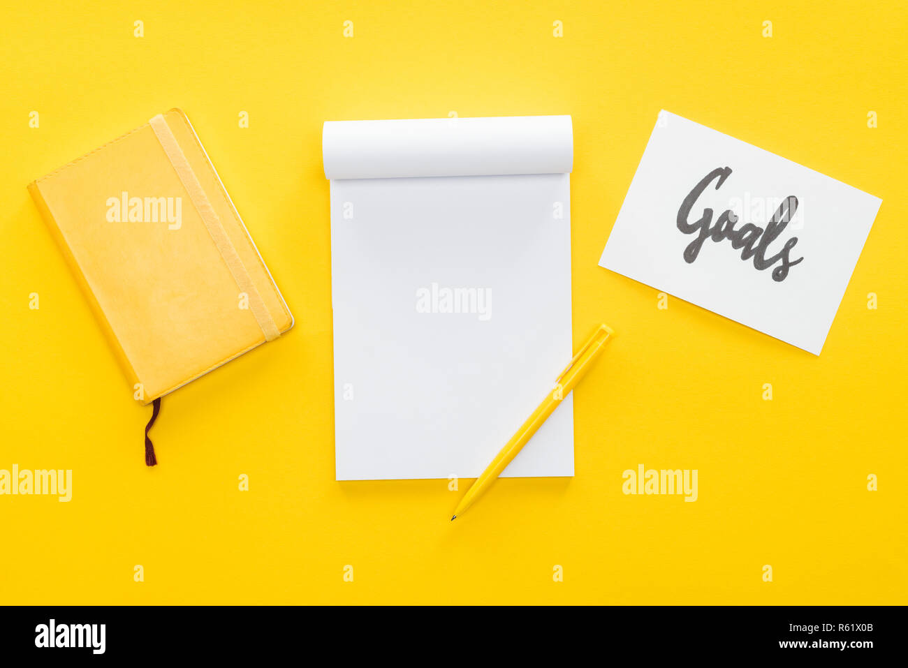 blank notebook and card with 'goals' lettering on yellow background ...
