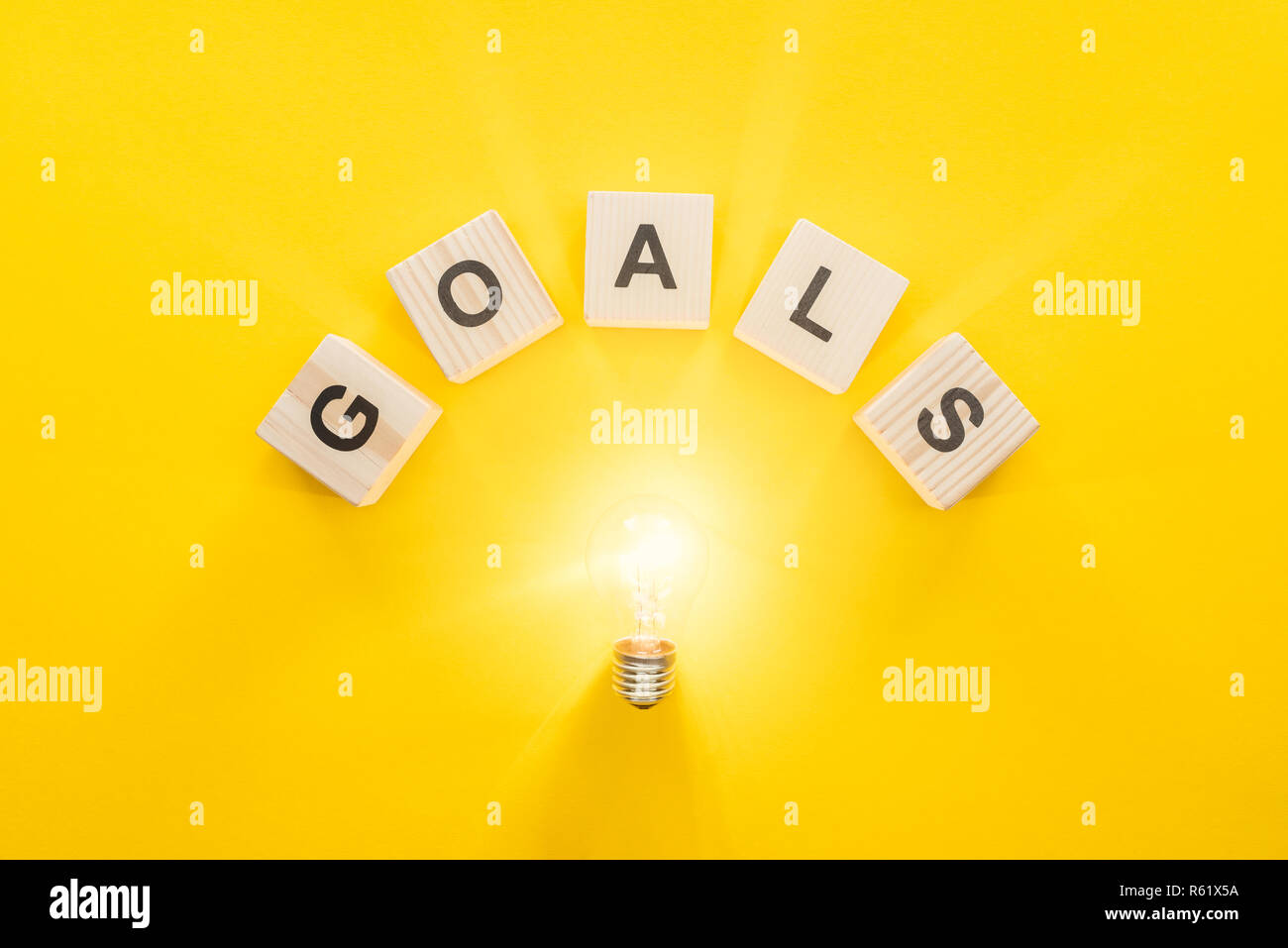 top view of glowing light bulb under 'goals' word made of wooden blocks ...
