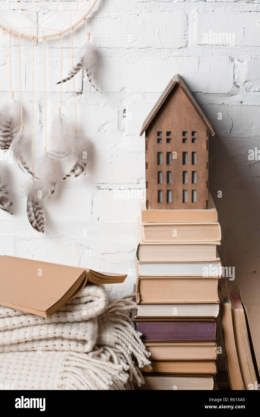 books, dream catcher and decorative wooden house near white brick wall ...