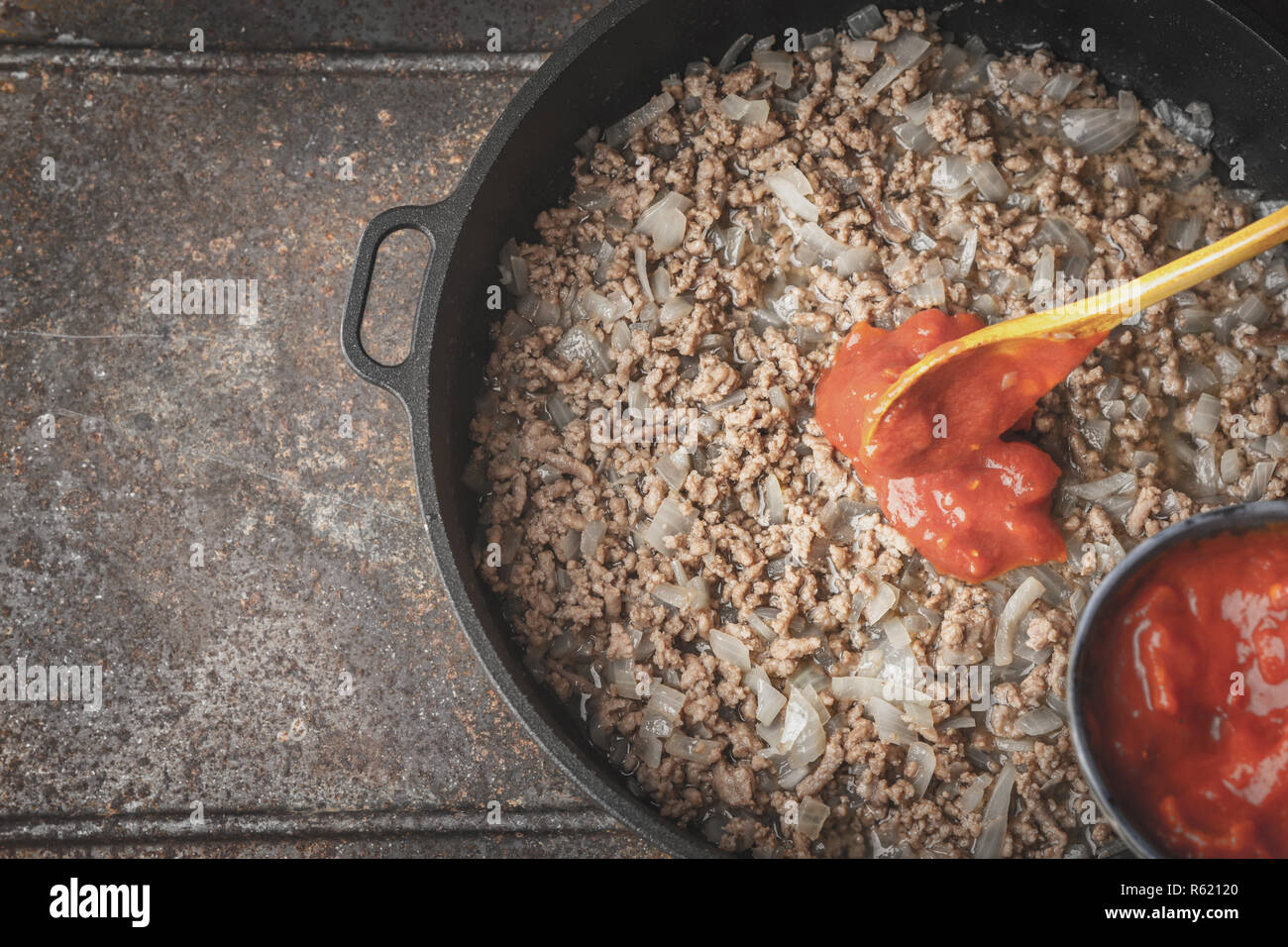 Fried minced meat with onion and chopped tomatoes in the pan top view ...