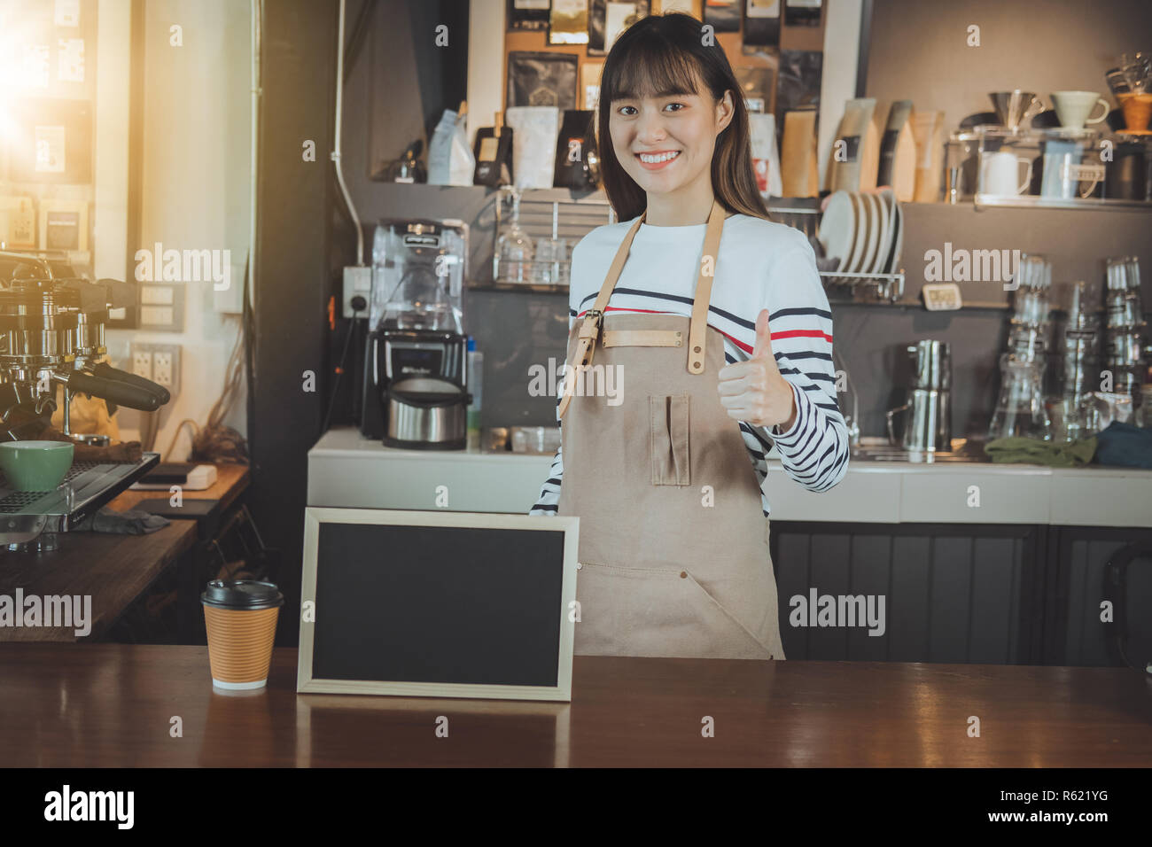 Asian barista standing at counter bar and hand showing thumb up. Cafe ...