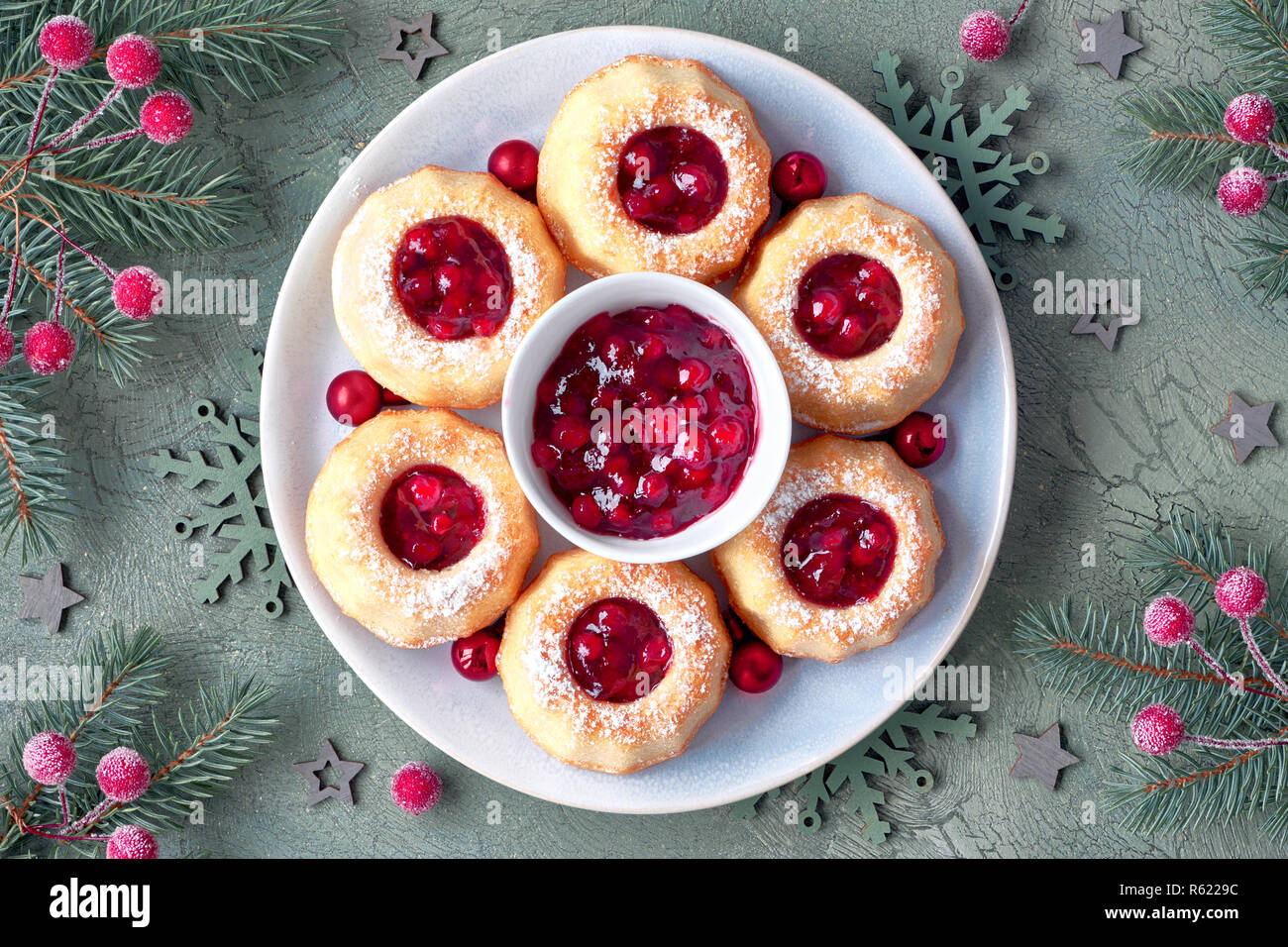 Mini bundt ring cakes with red whortleberry jam on green textured ...