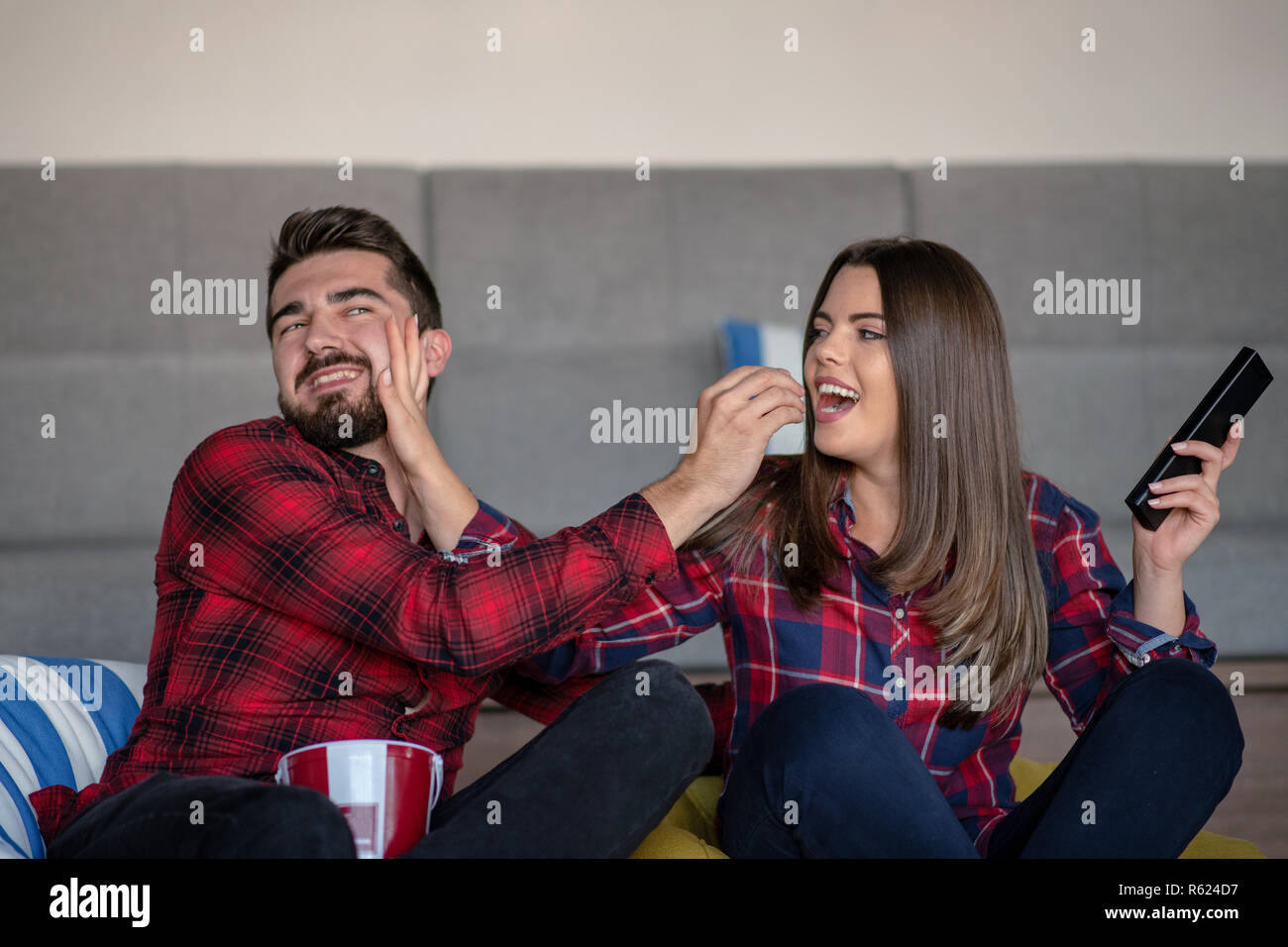 Couple fighting for remote control while watching TV at home Stock ...