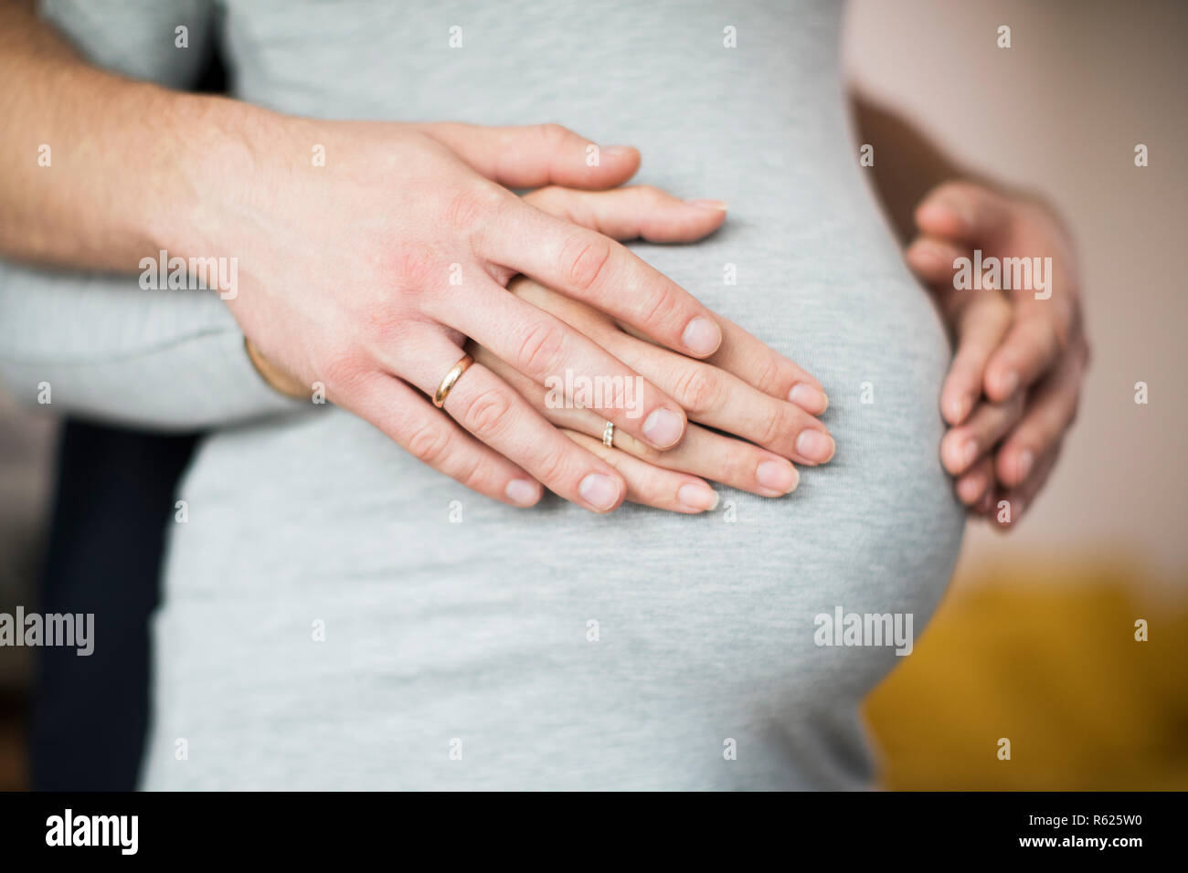 Close Up Of Male And Female Hands Resting On Pregnant Womans Stomach ...