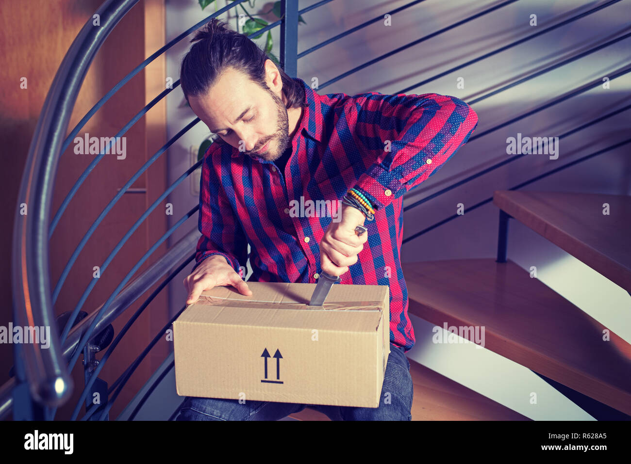man sitting in corridor and opening a package Stock Photo - Alamy