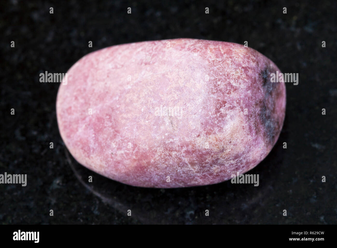 tumbled rhodonite gem on dark background Stock Photo - Alamy