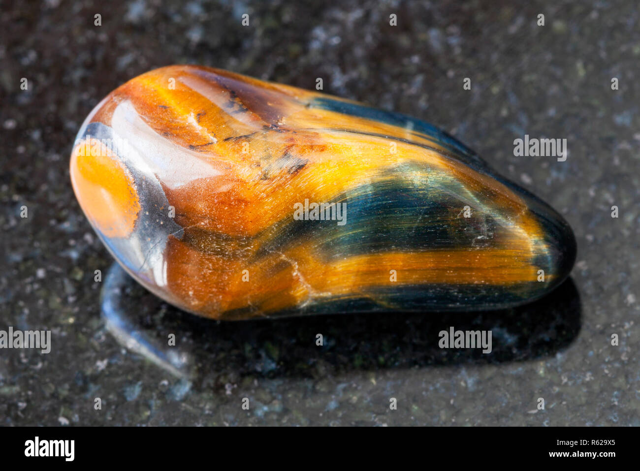 tumbled tiger-eye and hawk-eye gemstone on dark Stock Photo - Alamy