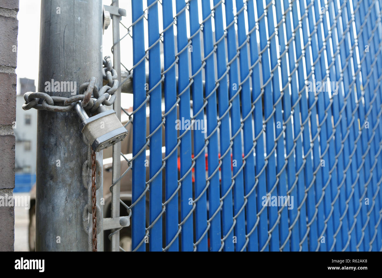 Heavy-duty padlock and chain on blue security gate Stock Photo - Alamy