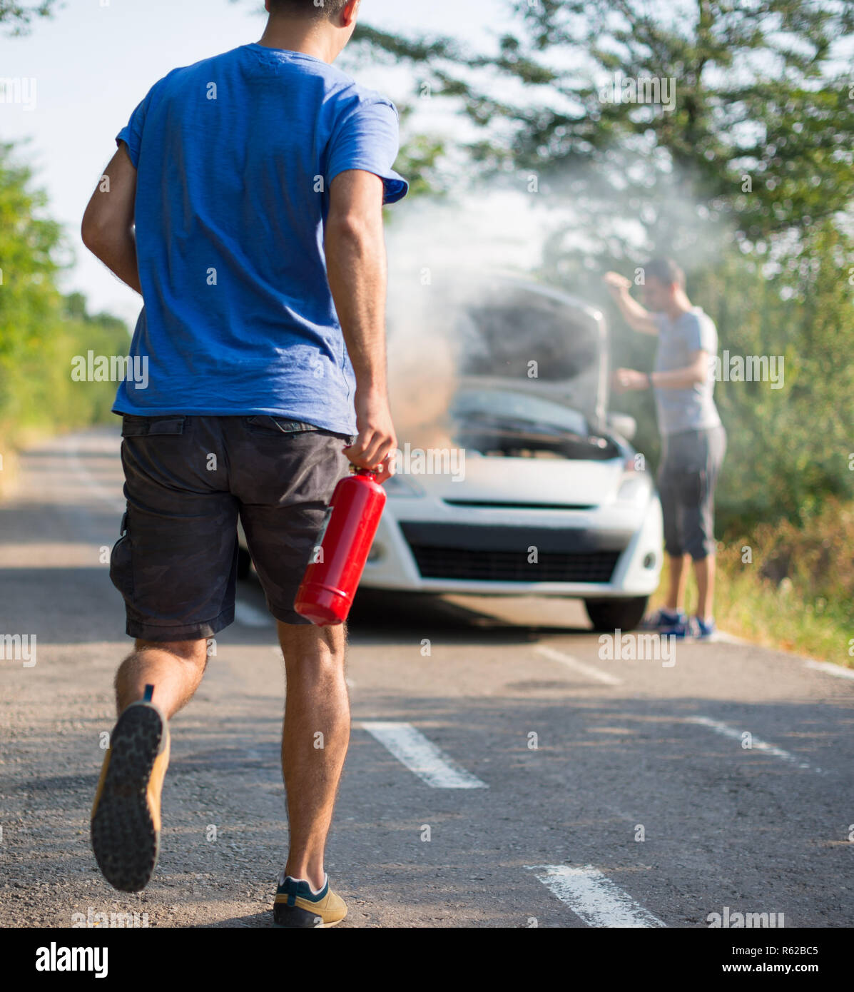 Man running with a car extinguisher to help another driver to ...