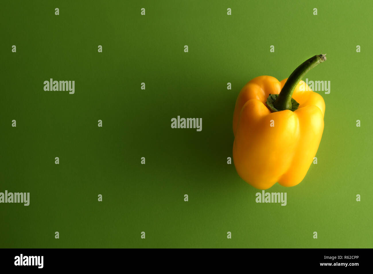 One yellow sweet papper on green background, viewed from above with ...