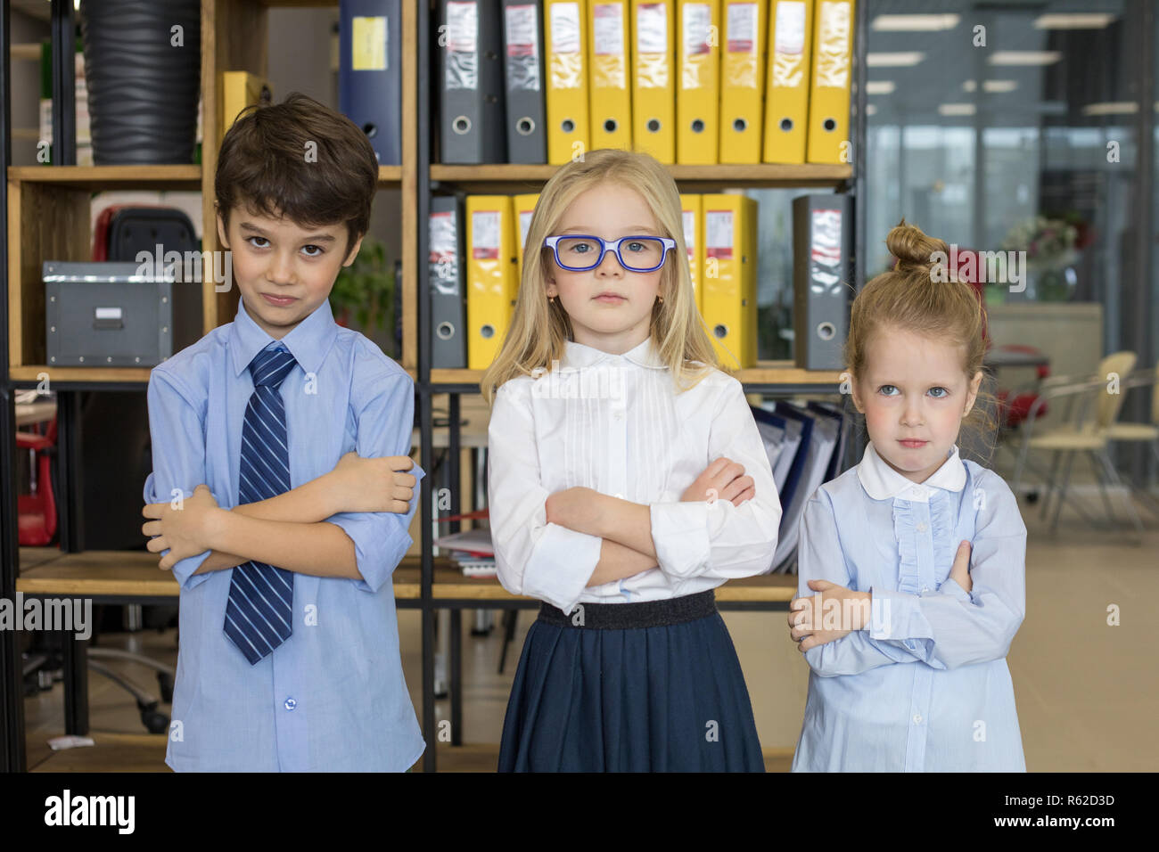 Three young children in business clothes are standing in the office ...