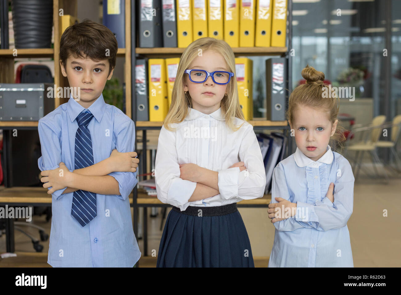 Three young children in business clothes are standing in the office ...