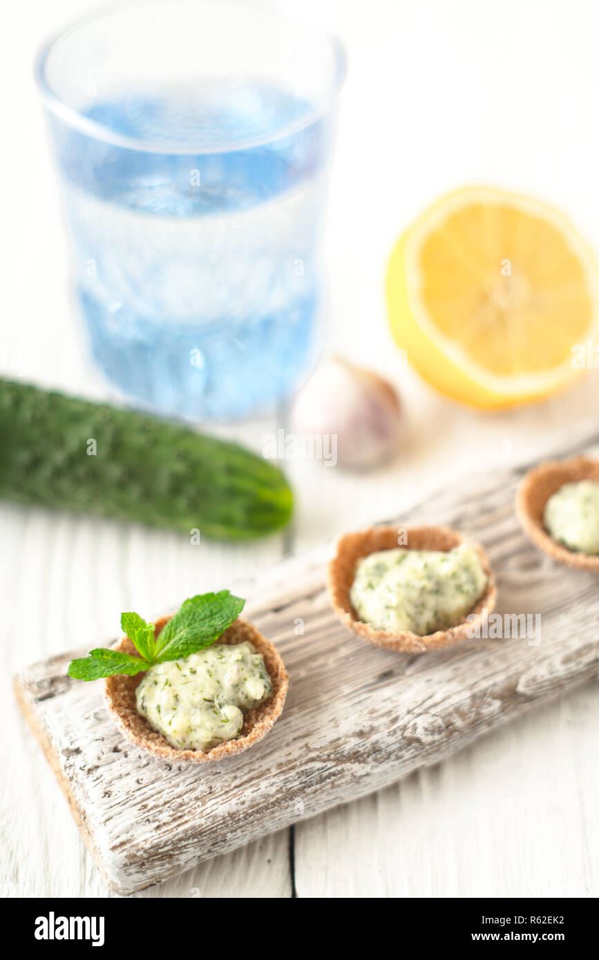 Bread with tzatziki on the white wooden board on the blue table ...
