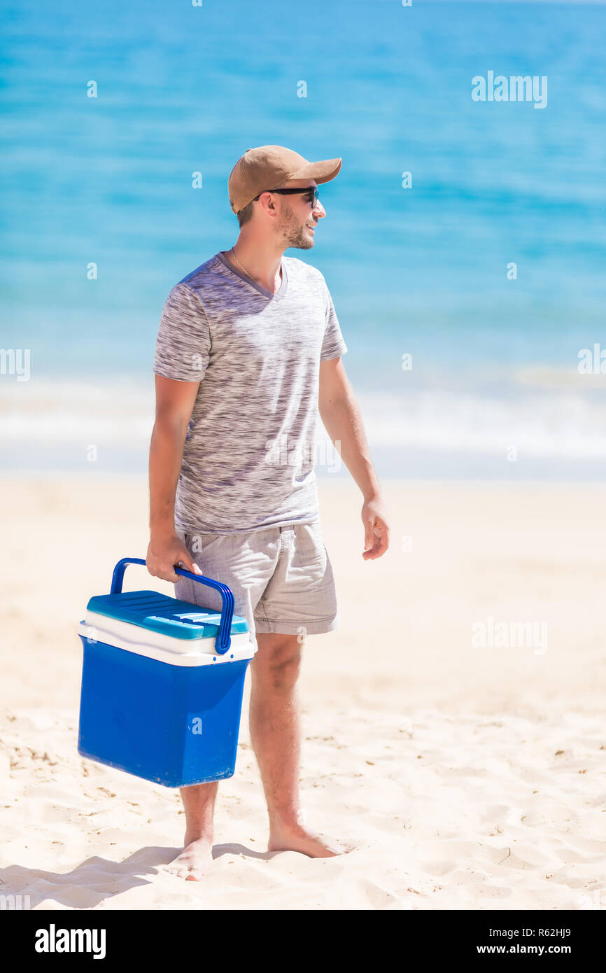 Young man carrying cooler with lots of beer bottles during party at ...