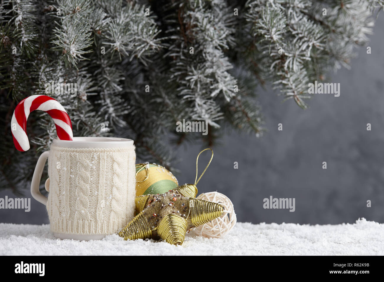 Knitted winter cup with hot chocolate and candy cane on snowy table ...