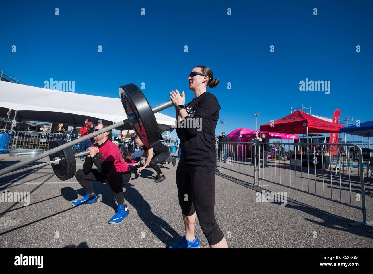 U.S. military and civilian members workout on a miniature obstacle rig ...