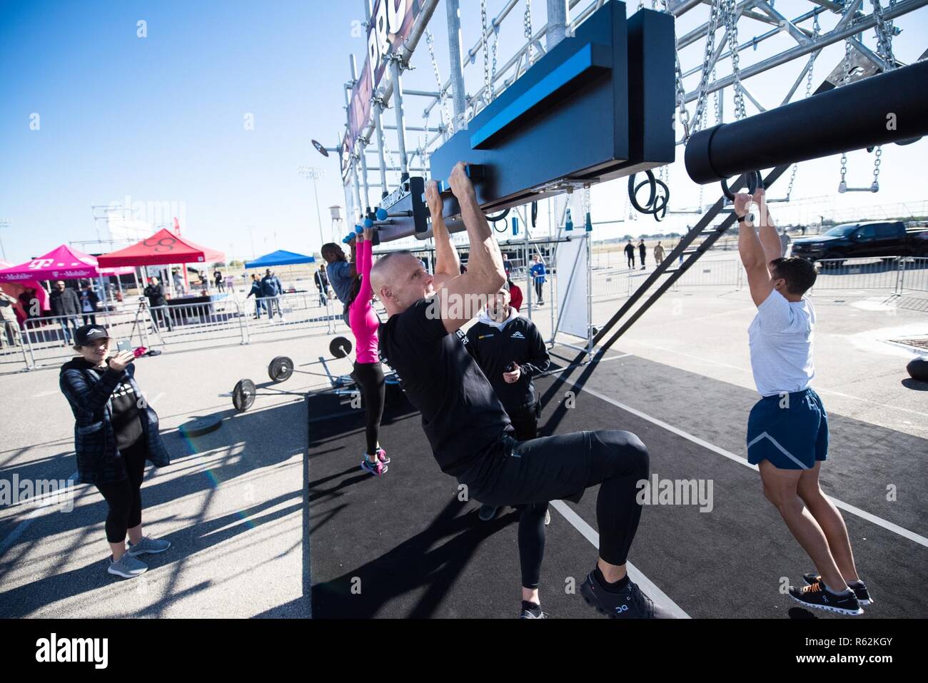 U.S. military and civilian members workout on a miniature obstacle rig ...