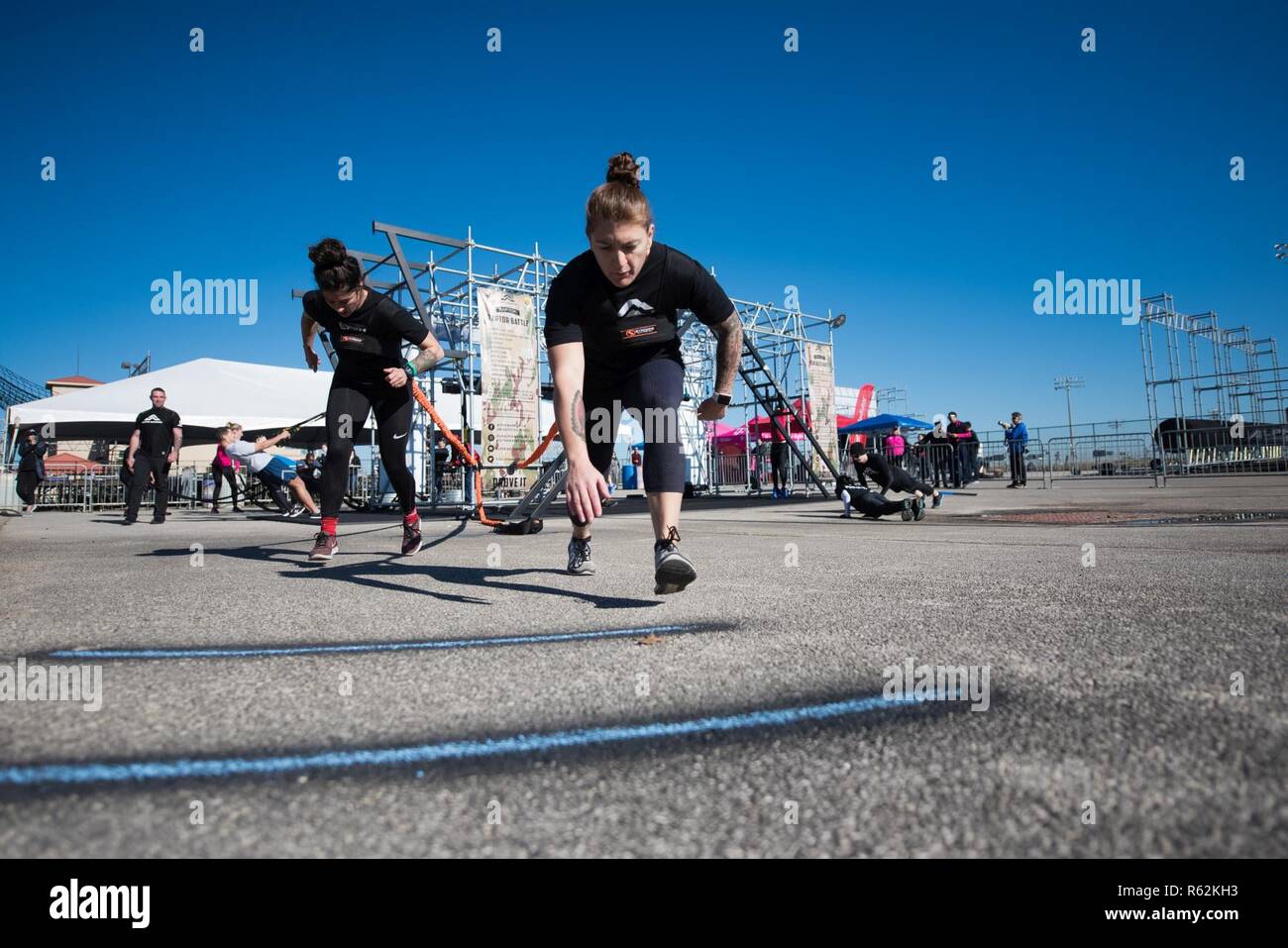 U.S. military and civilian members workout on a miniature obstacle rig ...