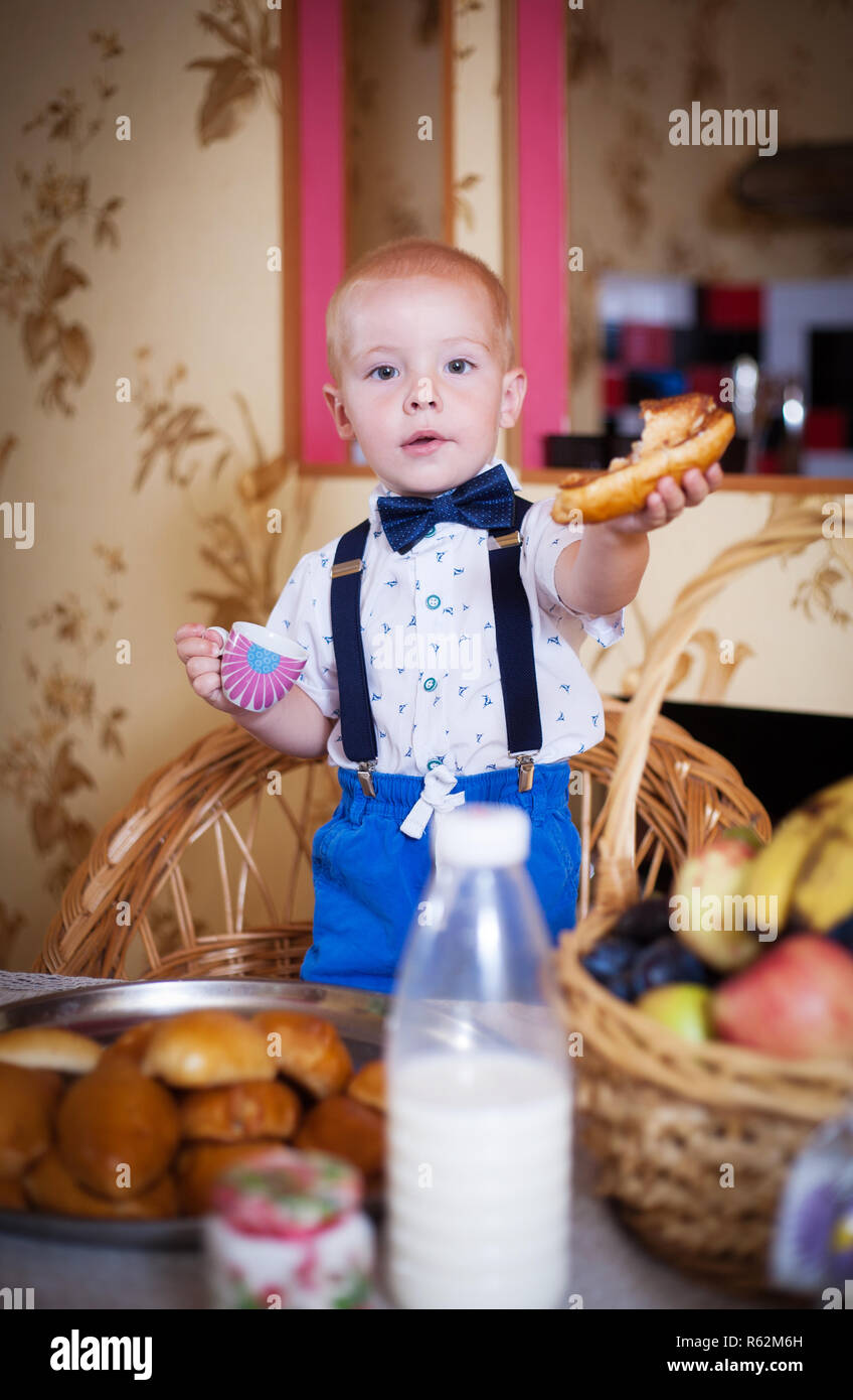 Little boy eating a pie in the kitchen at the table. Shooting in the ...