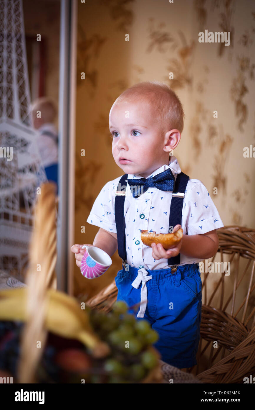 Little boy eating a pie in the kitchen at the table. Shooting in the ...