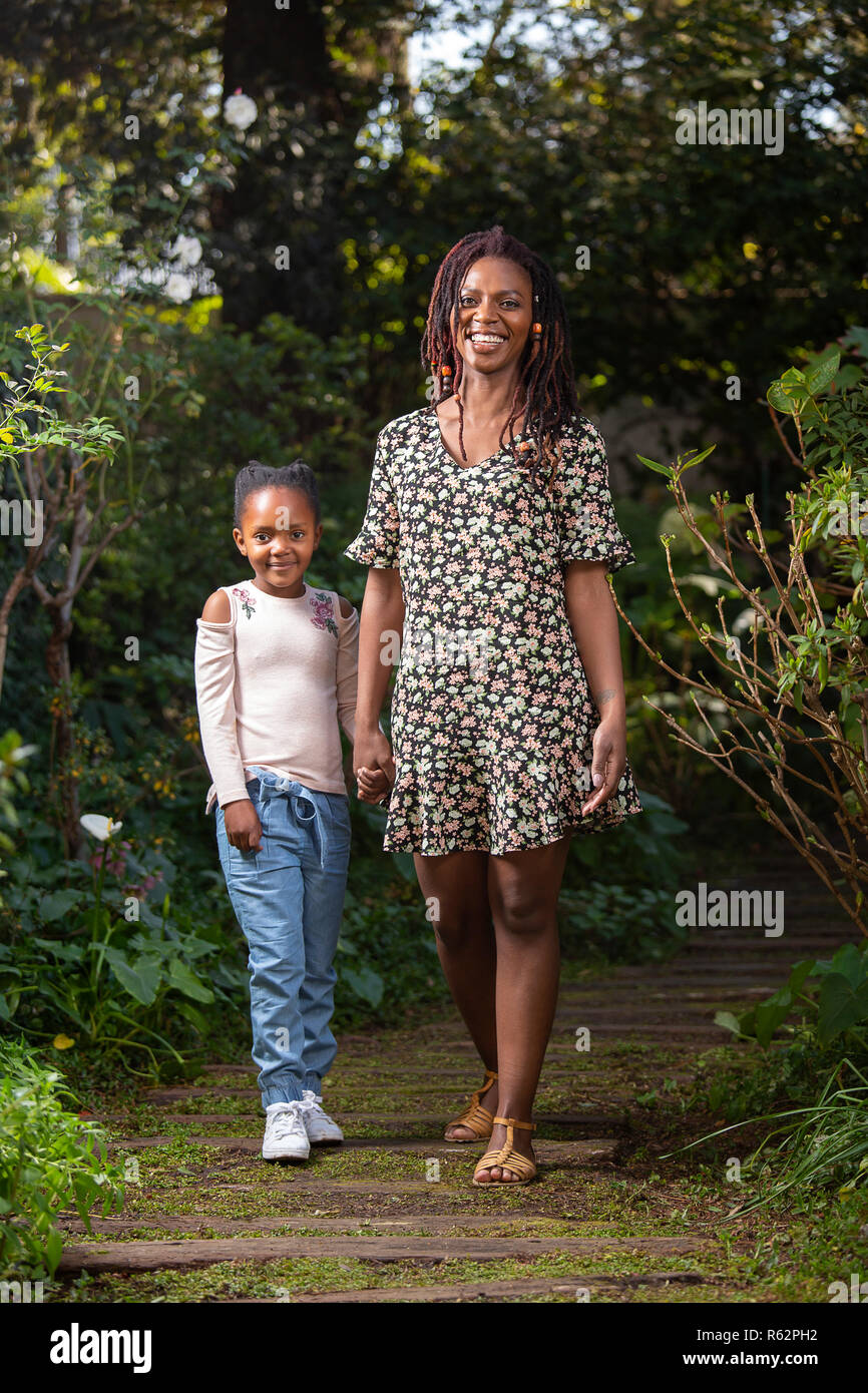 Mother and daughter holding hands walking down a garden path Stock Photo - Alamy