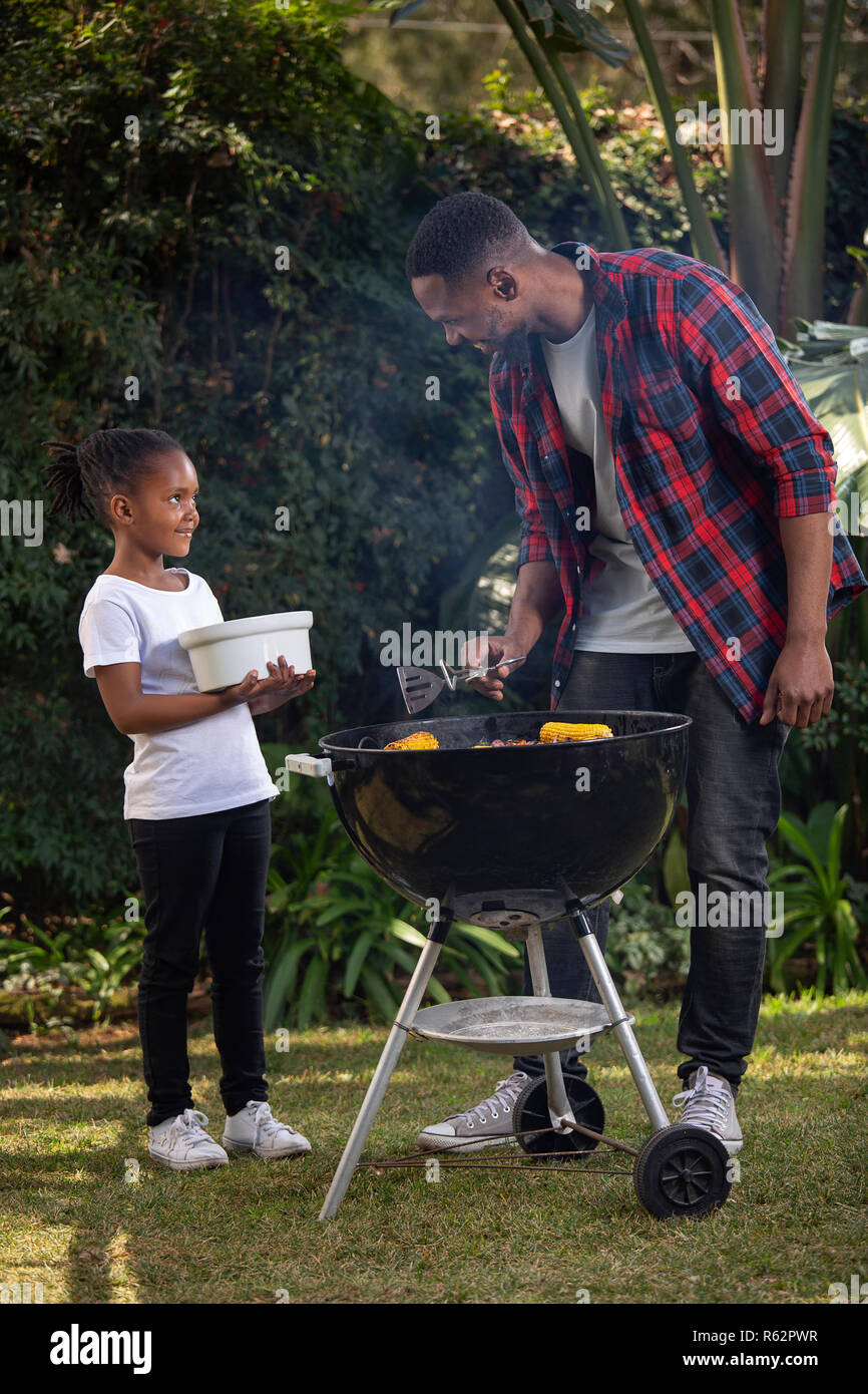 A girl helping her dad at a barbecue Stock Photo - Alamy