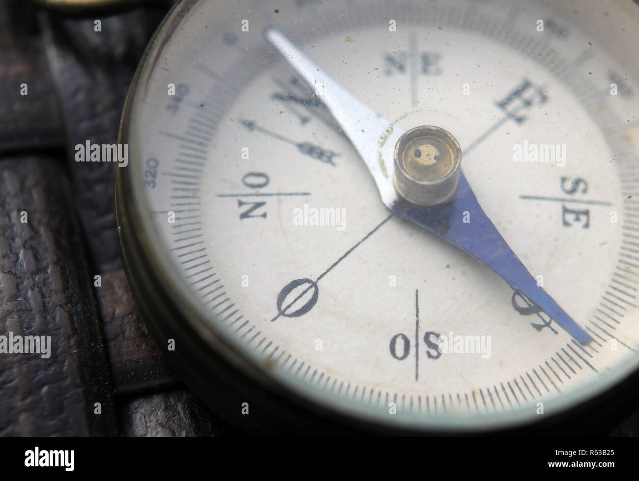 close up view of grunge compass points to true north on wooden ...