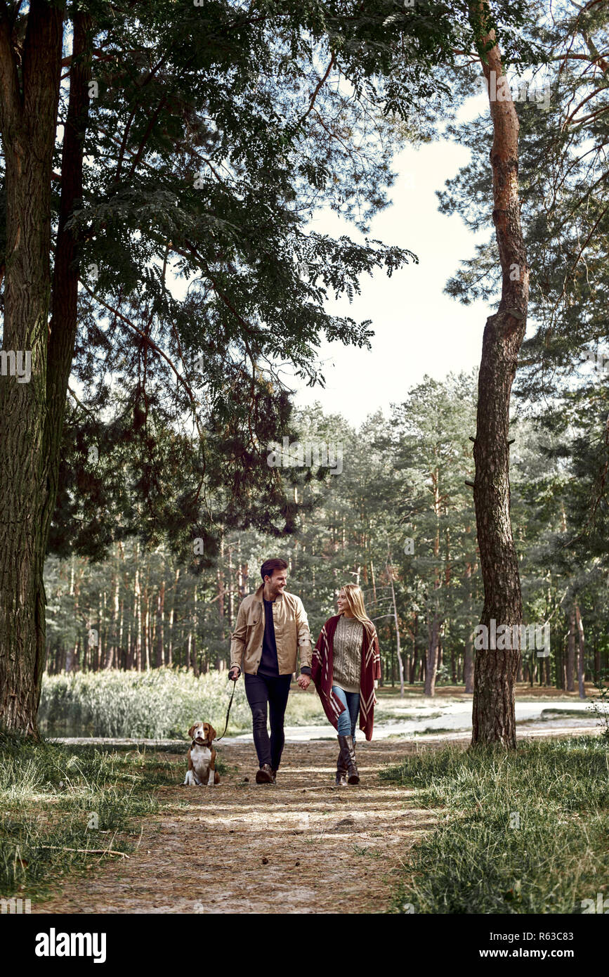 Young couple are walking with dog in forest Stock Photo - Alamy