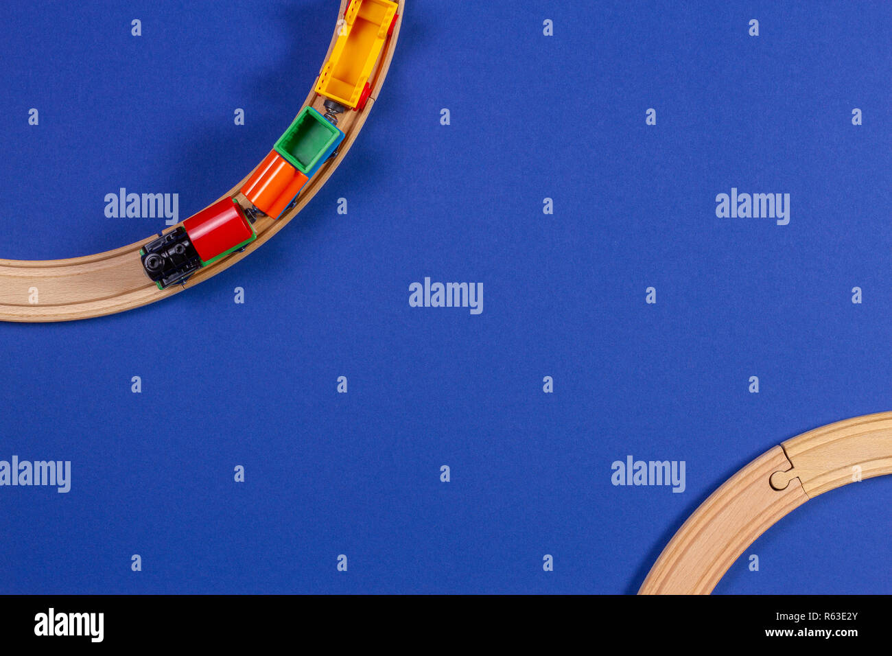 Toy trains and wooden rails on blue color background Stock Photo - Alamy