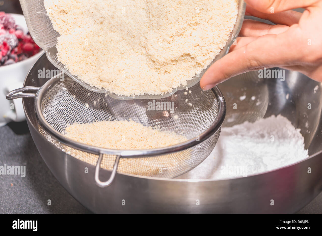 cook mixes and sieves almond powder in flour Stock Photo - Alamy