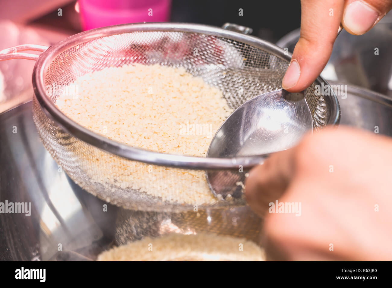 cook mixes and sieves almond powder in flour Stock Photo - Alamy