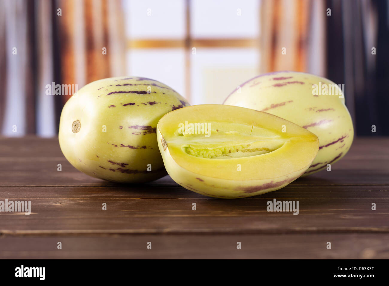 Group of two whole one half of fresh striped pepino melon with silk ...