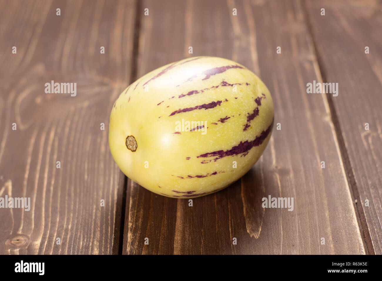 One whole fresh striped pepino melon on brown wood Stock Photo - Alamy