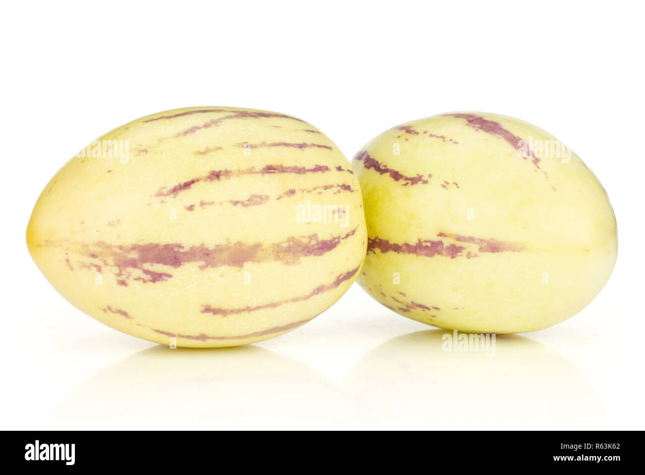 Group of two whole oval fresh striped pepino melon isolated on white ...