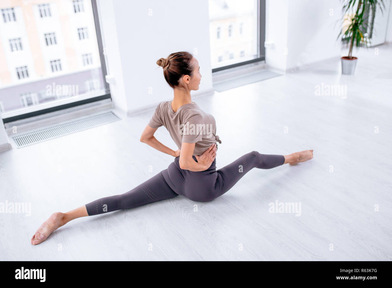 top angle view. girl with hands on the hips doing splits. full length ...
