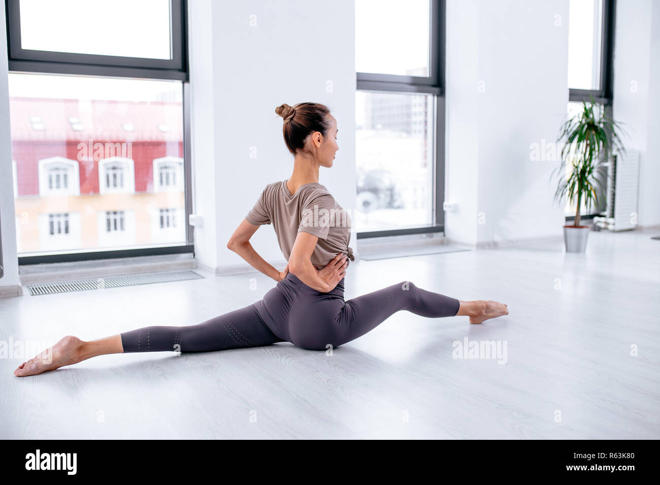a body position . young woman doing a front split with right leg ...