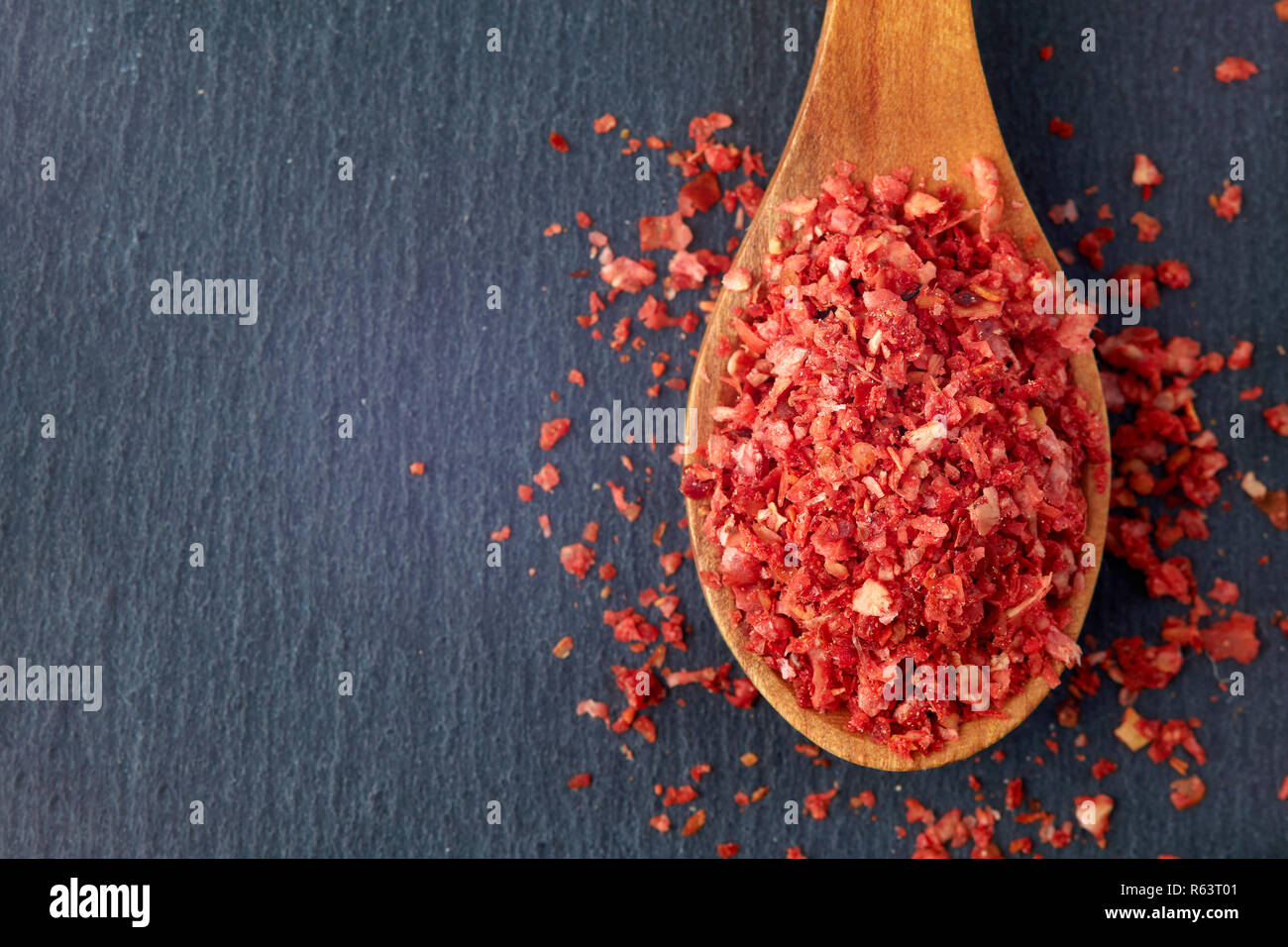 Dried chopped chili pepper in wooden spoon. Top view with copy space ...
