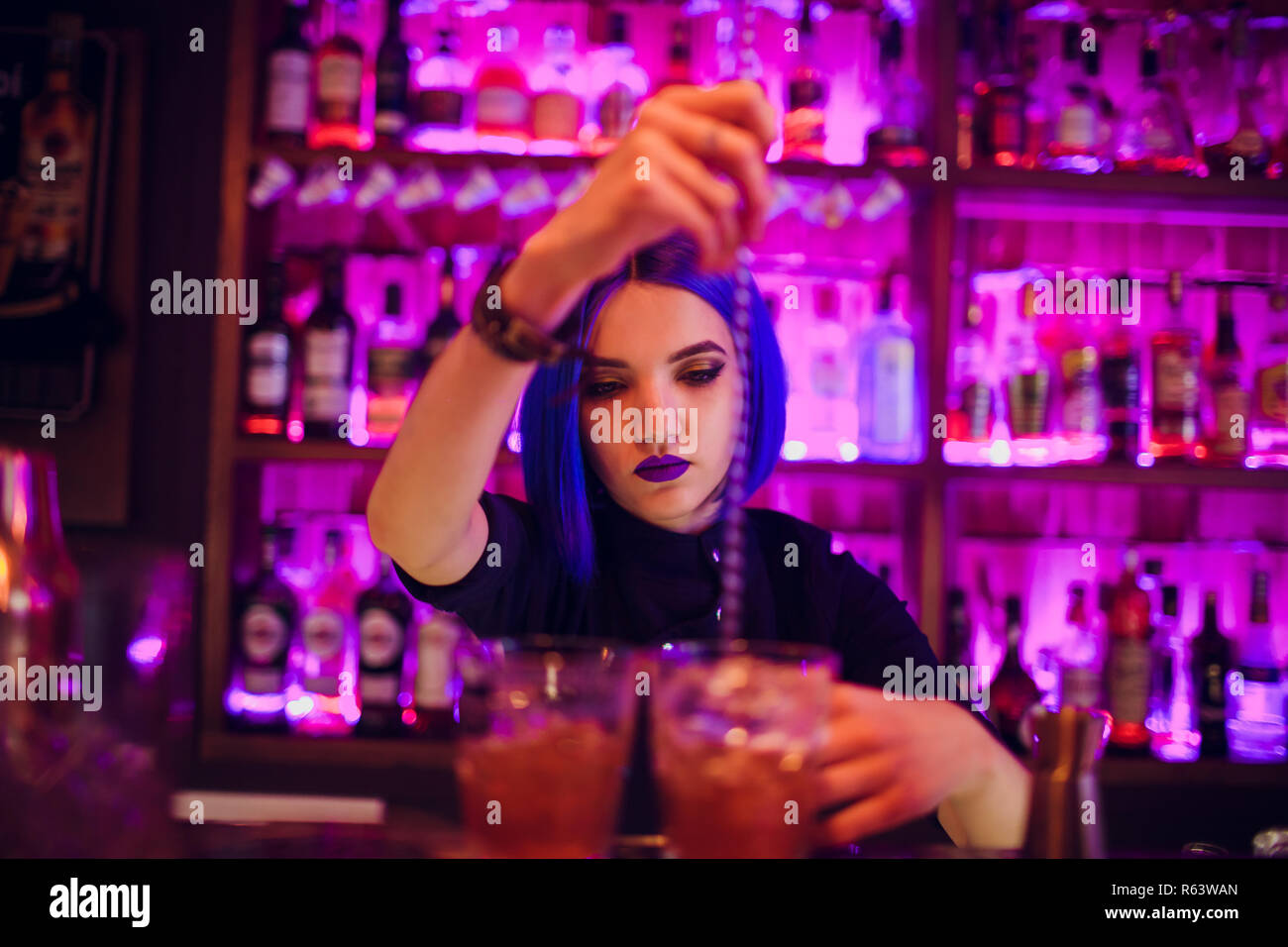 female bartender. girl with blue hair. cocktail making in night bar ...
