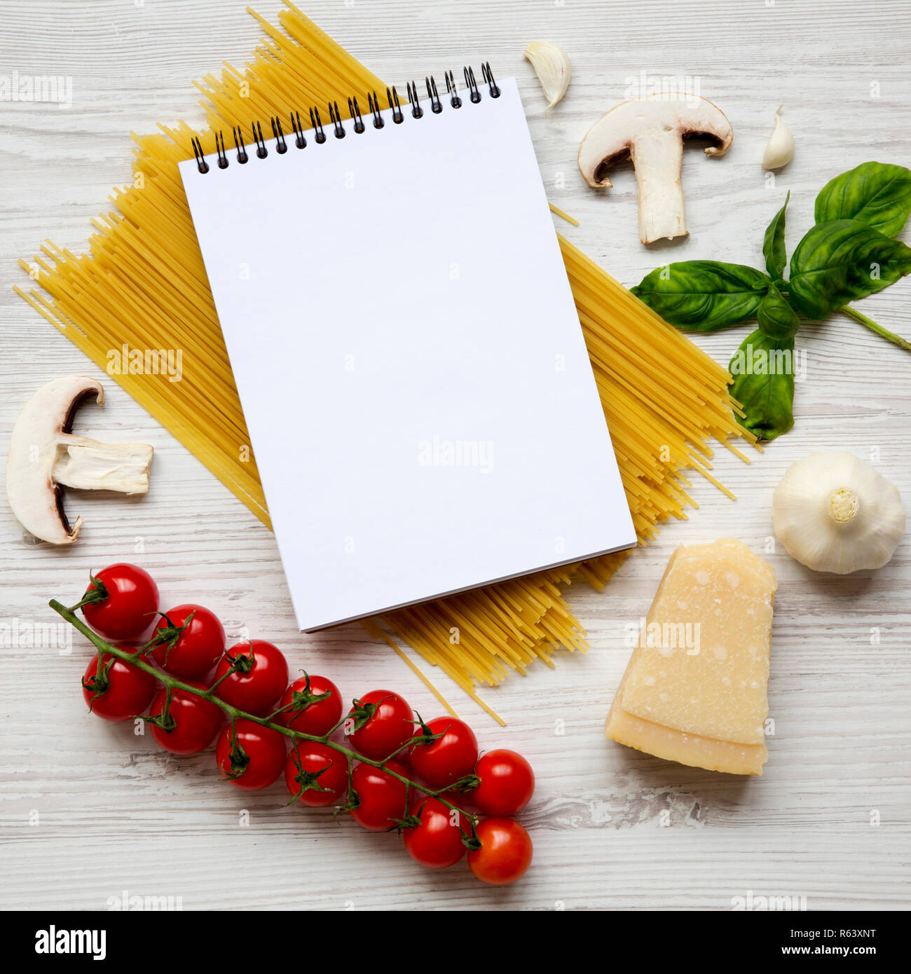 Different ingredients for cooking pasta with blank notepad on a white ...