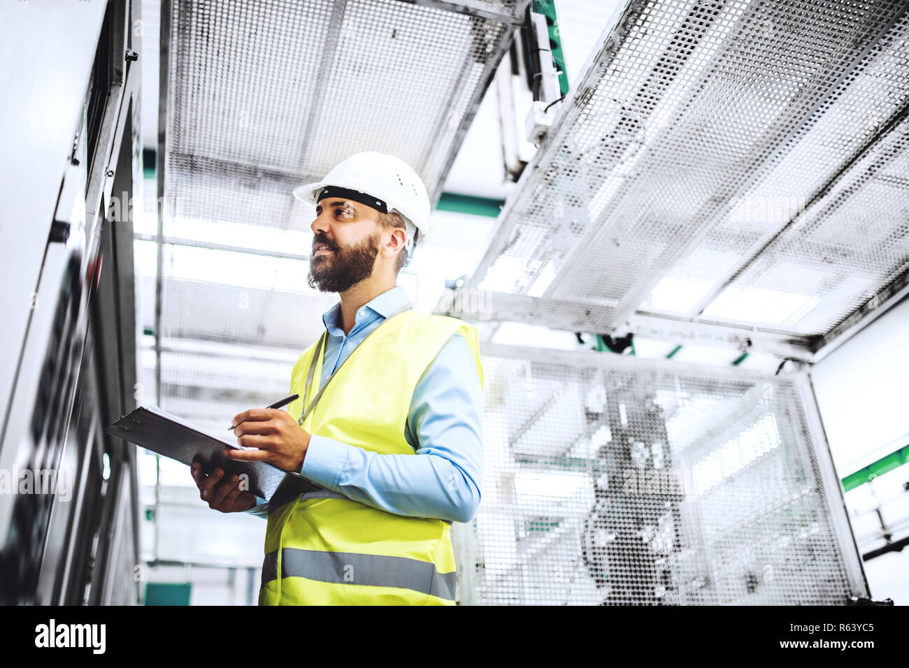 A portrait of an industrial man engineer with clipboard in a factory ...
