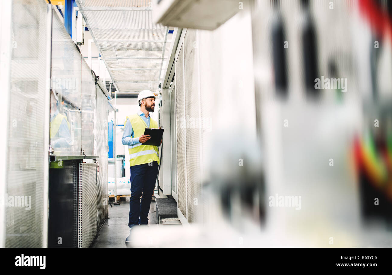 An industrial man engineer with clipboard in a factory, working. Copy ...