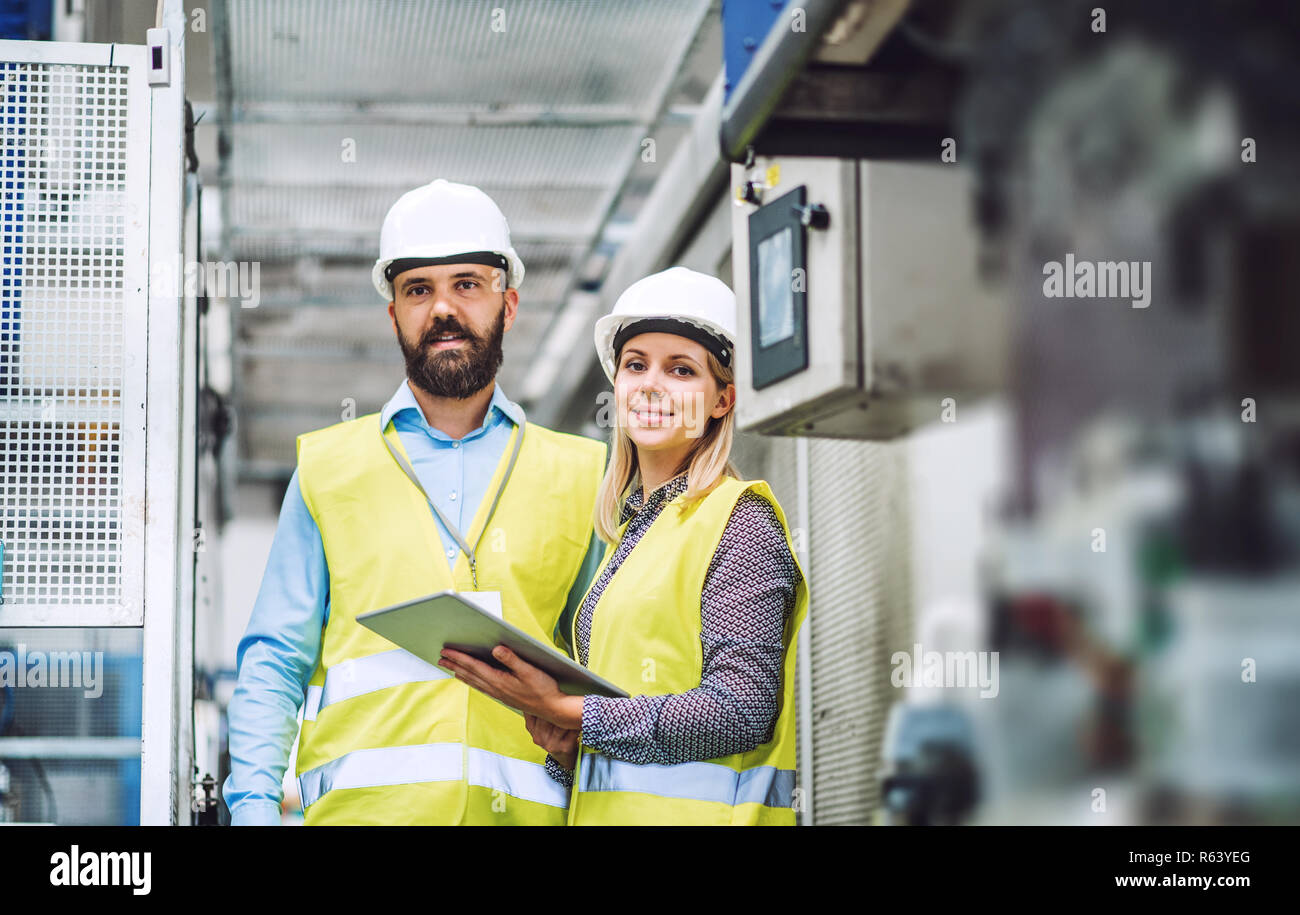 A portrait of an industrial man and woman engineer with tablet in a ...